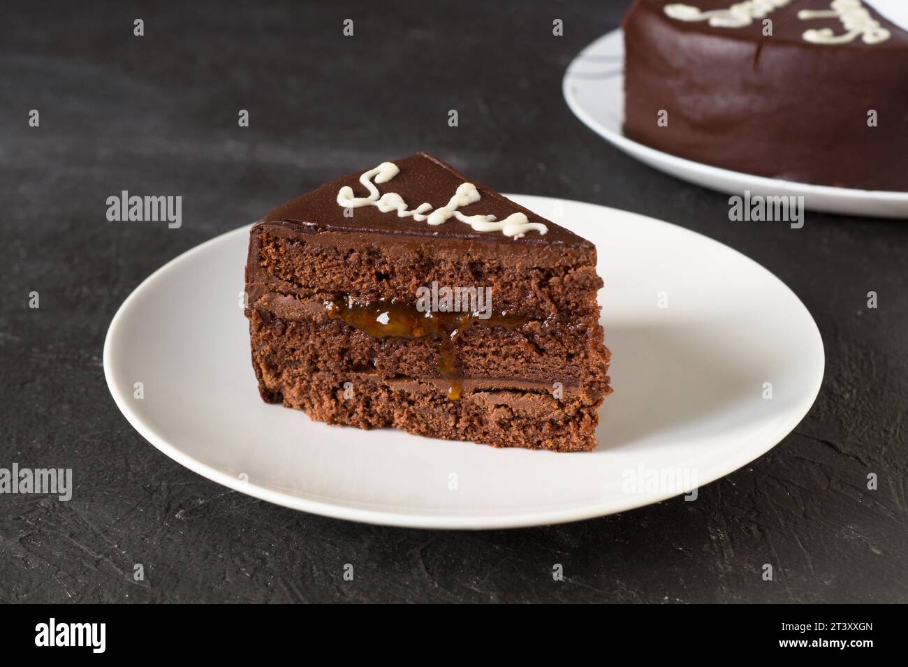 Chocolate cake Sacher with apricot jam on white plate. Traditional ...