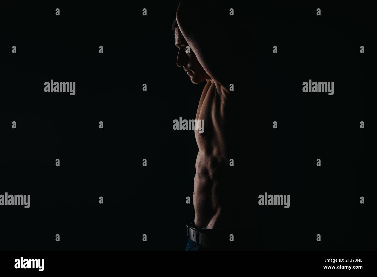 Strong guy showing his abs posing with his arms above his head. Side ...
