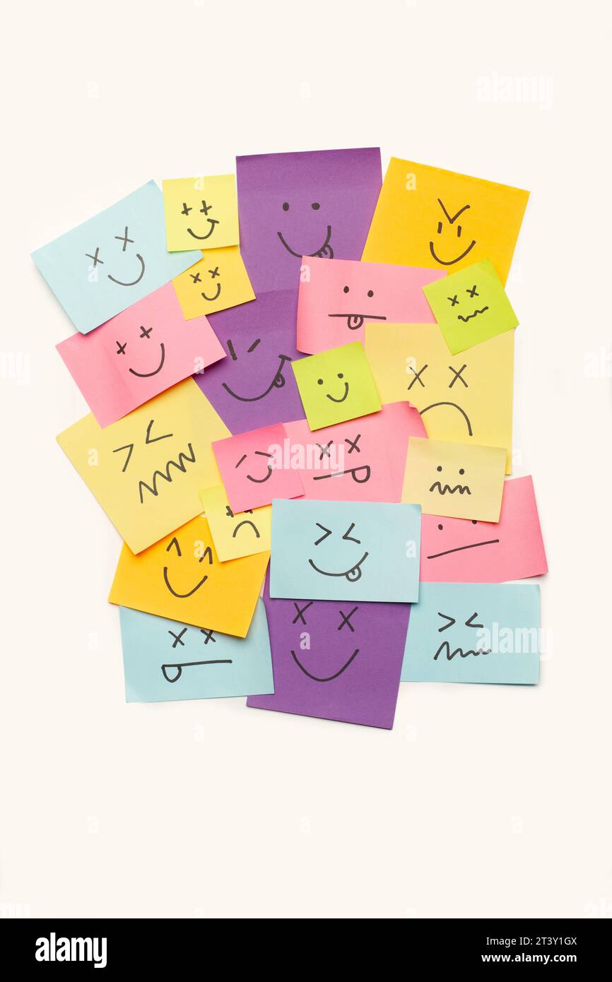 Colored paper notes with drawings of different face emotions on a white ...