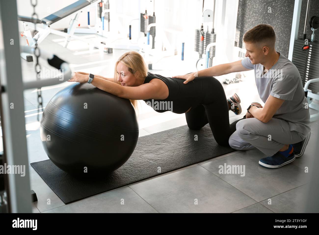 Expectant mother performs relaxing exercises for her back with fitball ...