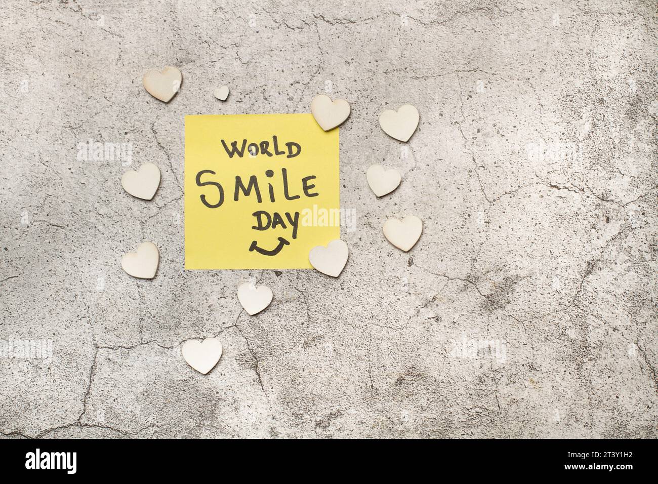 World smile day write in a paper note and white hearts on a gray stone ...
