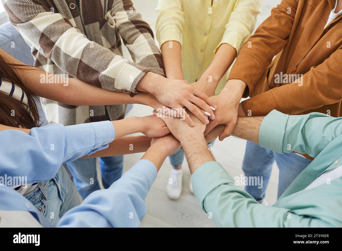 Happy smiling people friends putting their arms together in a stack ...