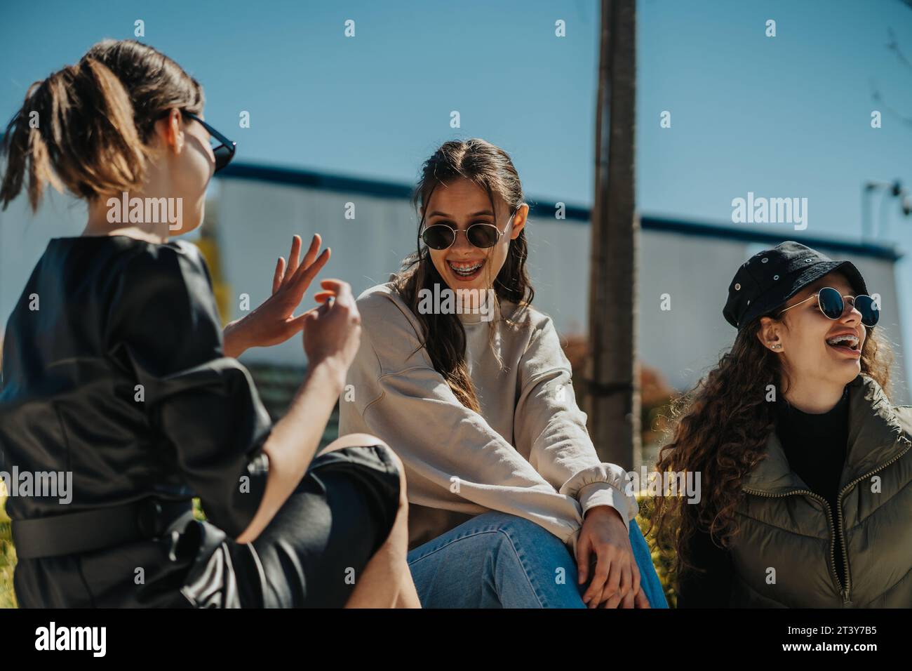 Young girl in black overcoat begging her long haired brunette friend to ...