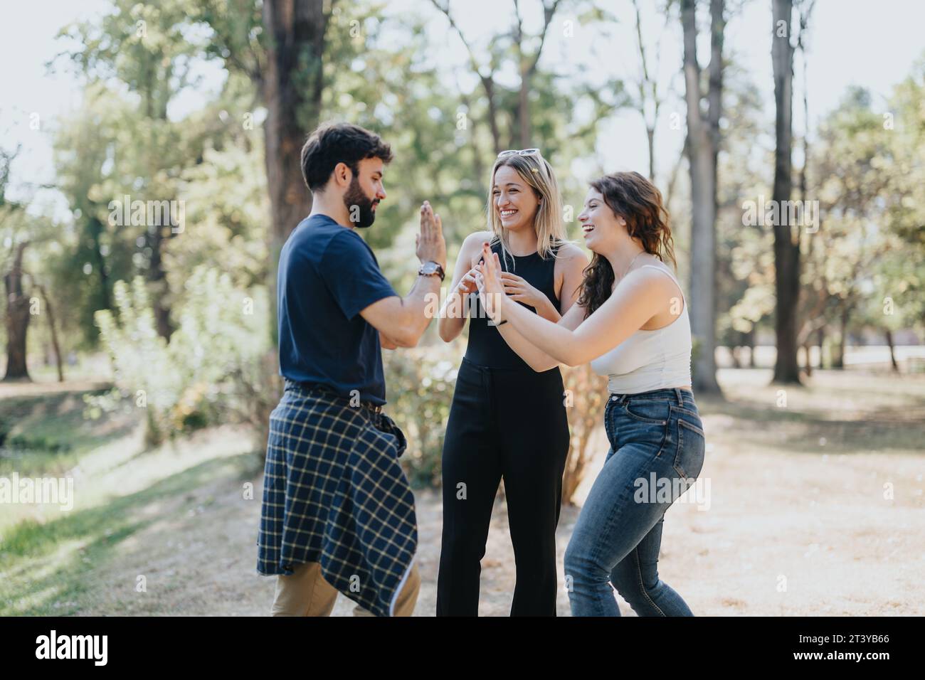 Young friends in a city park, surrounded by nature, happily chatting ...