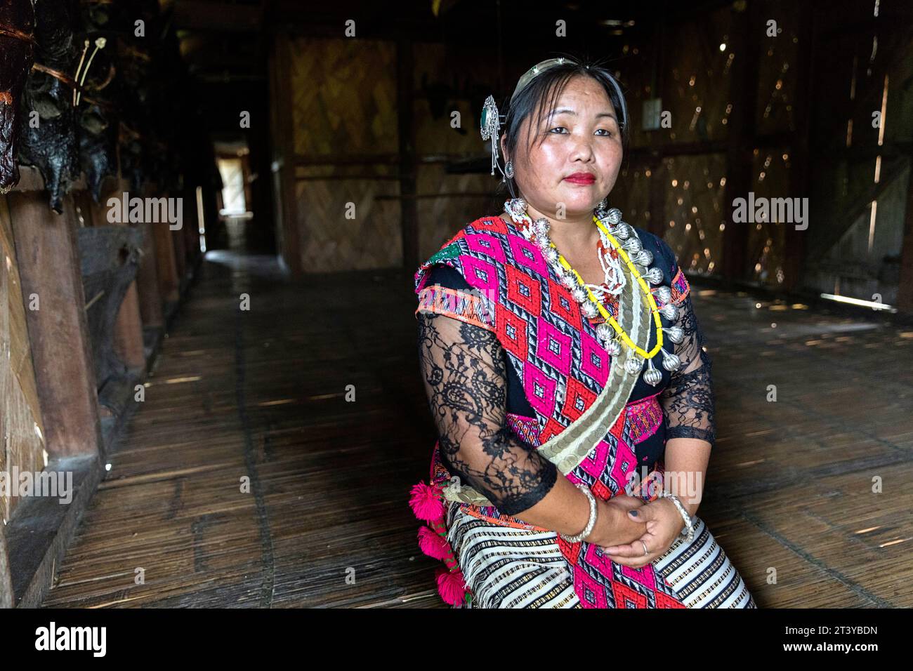 Woman from Adi tribe in traditional clothes sitting in front of wall ...