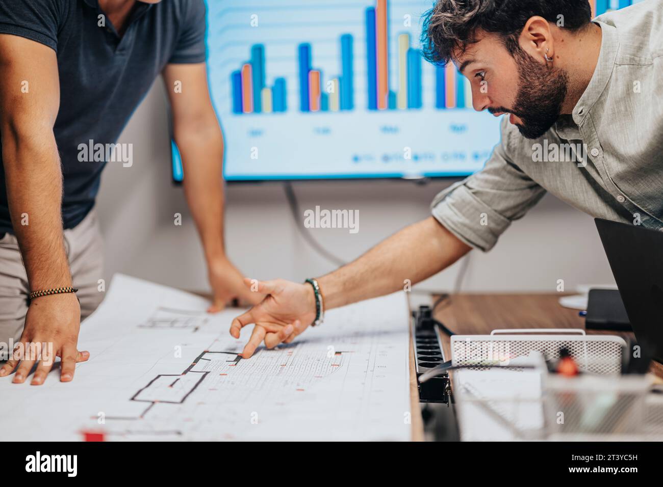 Multiracial professionals review architectural blueprints ...