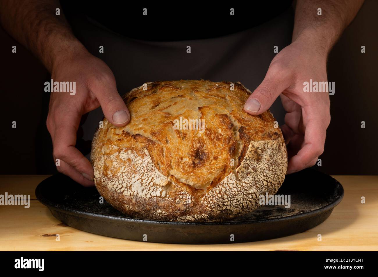 The hands of a young man handling sourdough bread, highlighting the ...