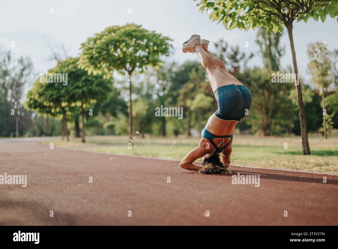 A fit girl displays strength and flexibility in a headstand pose amidst ...