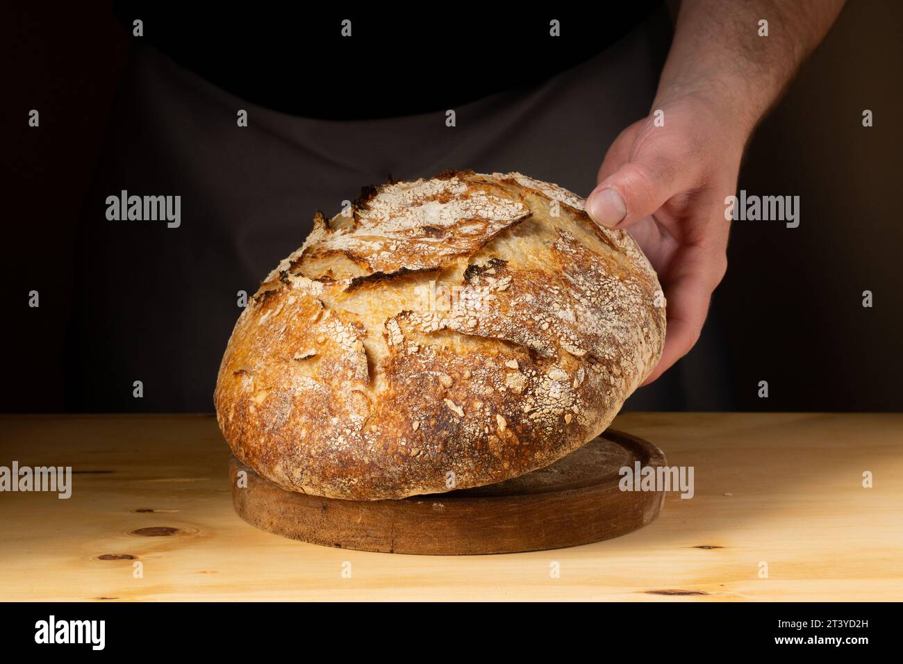 The hands of a young man handling sourdough bread, highlighting the ...