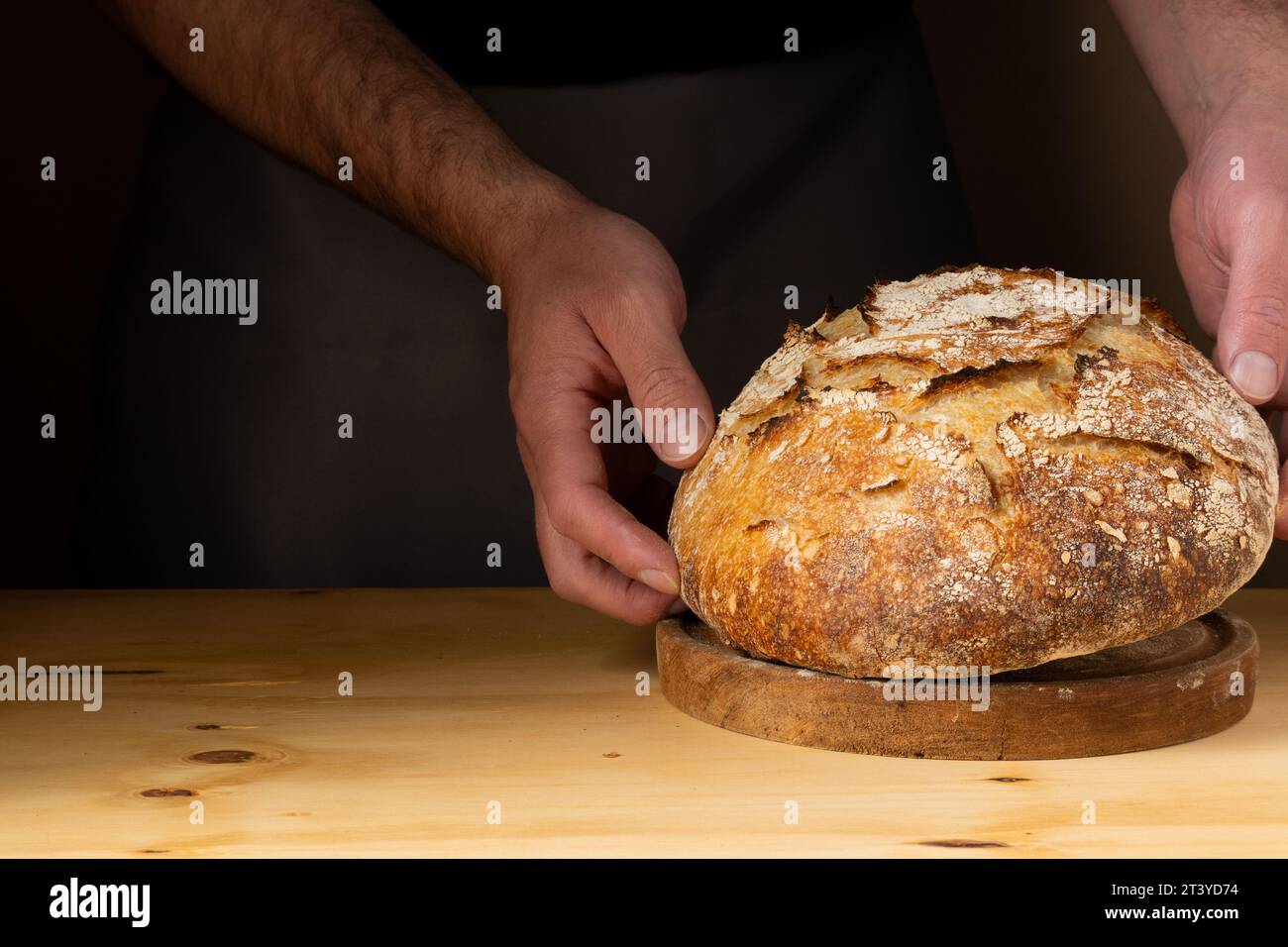 The hands of a young man handling sourdough bread, highlighting the ...