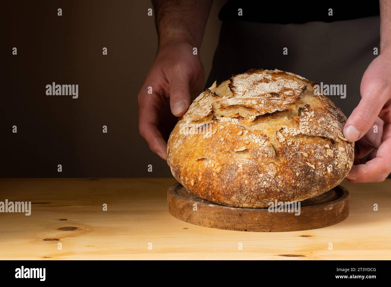 The hands of a young man handling sourdough bread, highlighting the ...