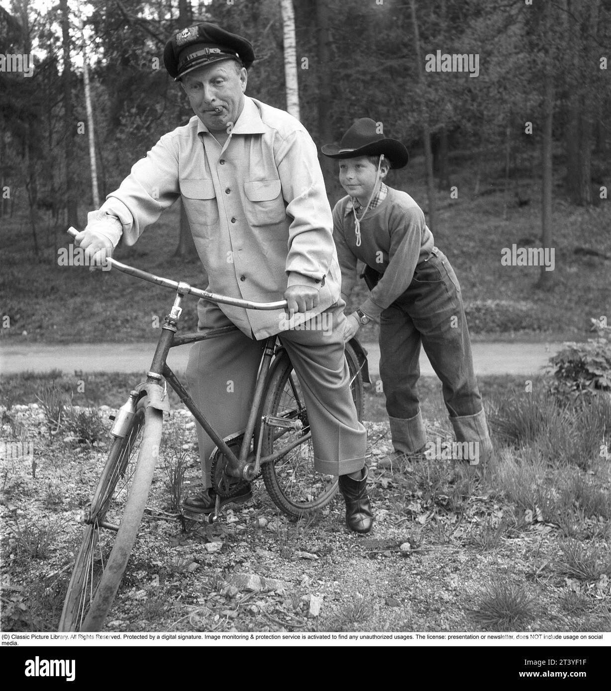 In the 1950s. A man pictured when trying to balance himself on a bicycle and is given help by ...