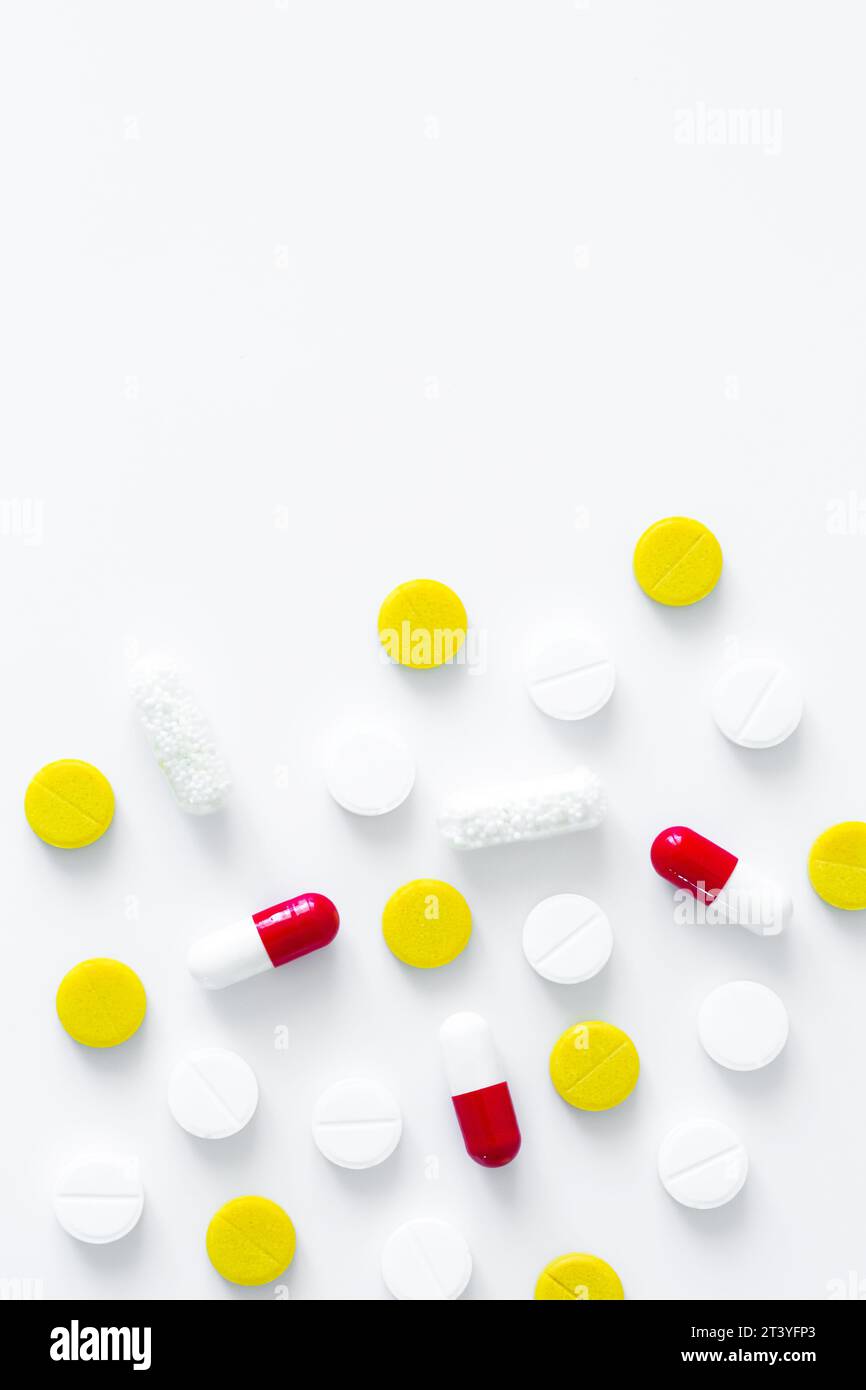 Top view of transparent tablets and colored pills scattered on white ...