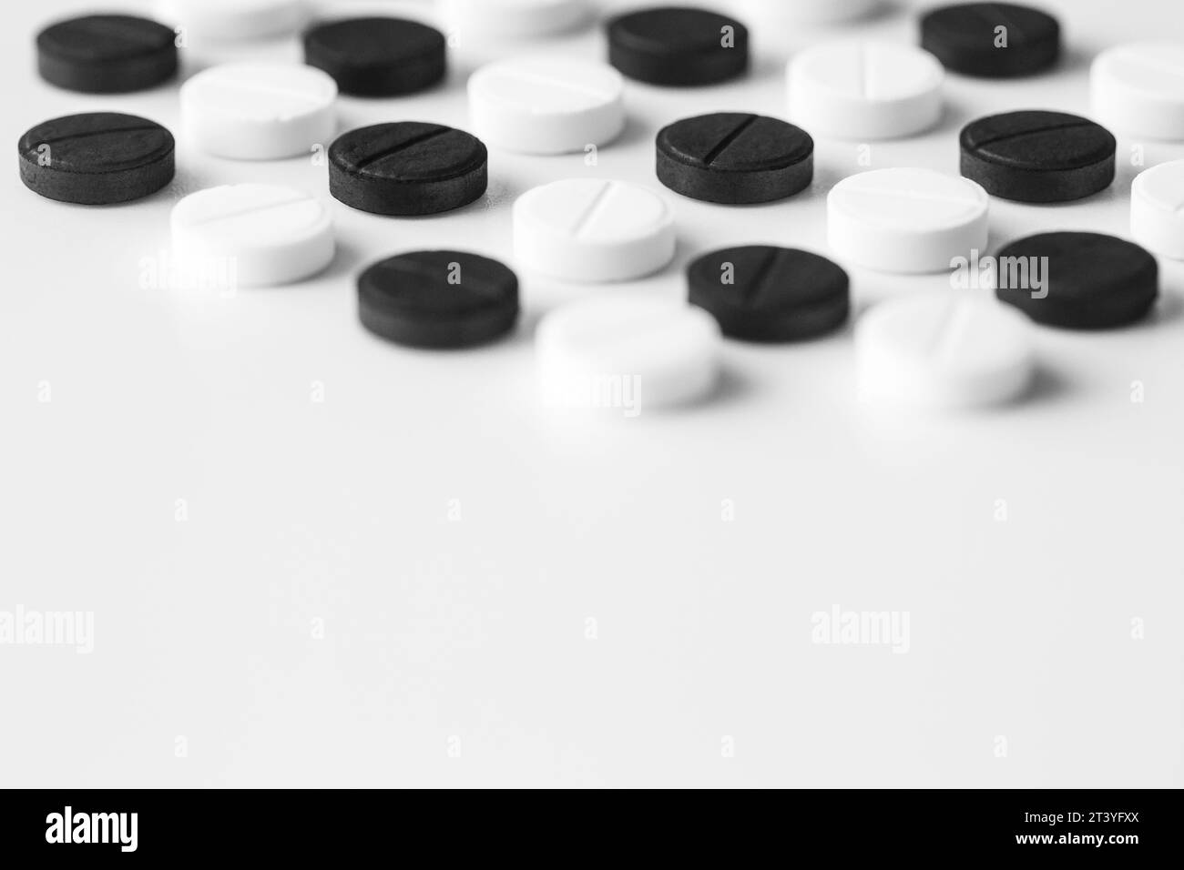 Close up of black and white pills lie exactly in a row on a white table ...