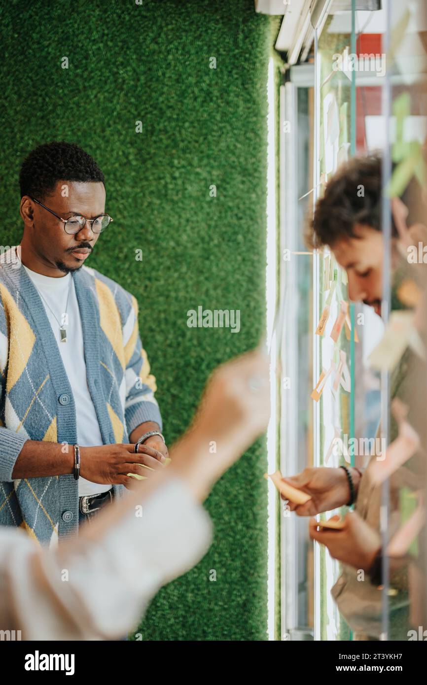 Multiracial business team share knowledge through a glass wall, writing ...