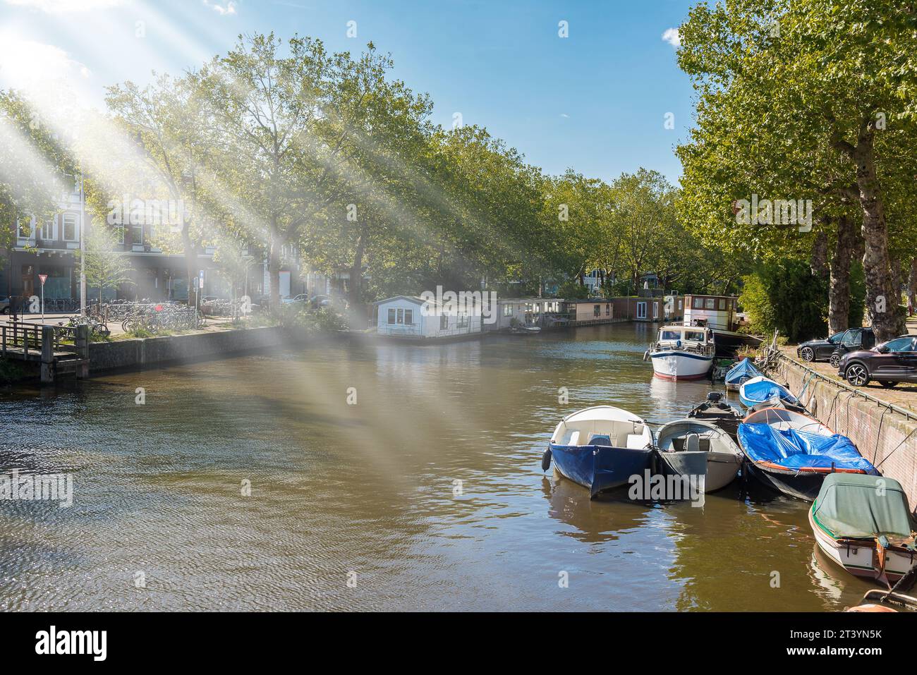 Sunburst over Amsterdam canal with boats houseboats and bridges Stock ...