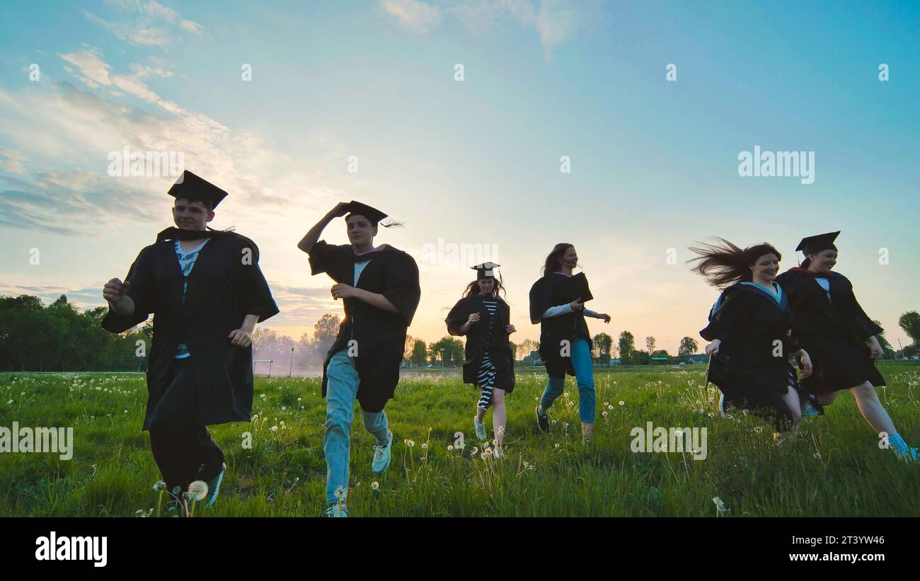 College graduates run off into the sunset in black robes Stock Photo ...