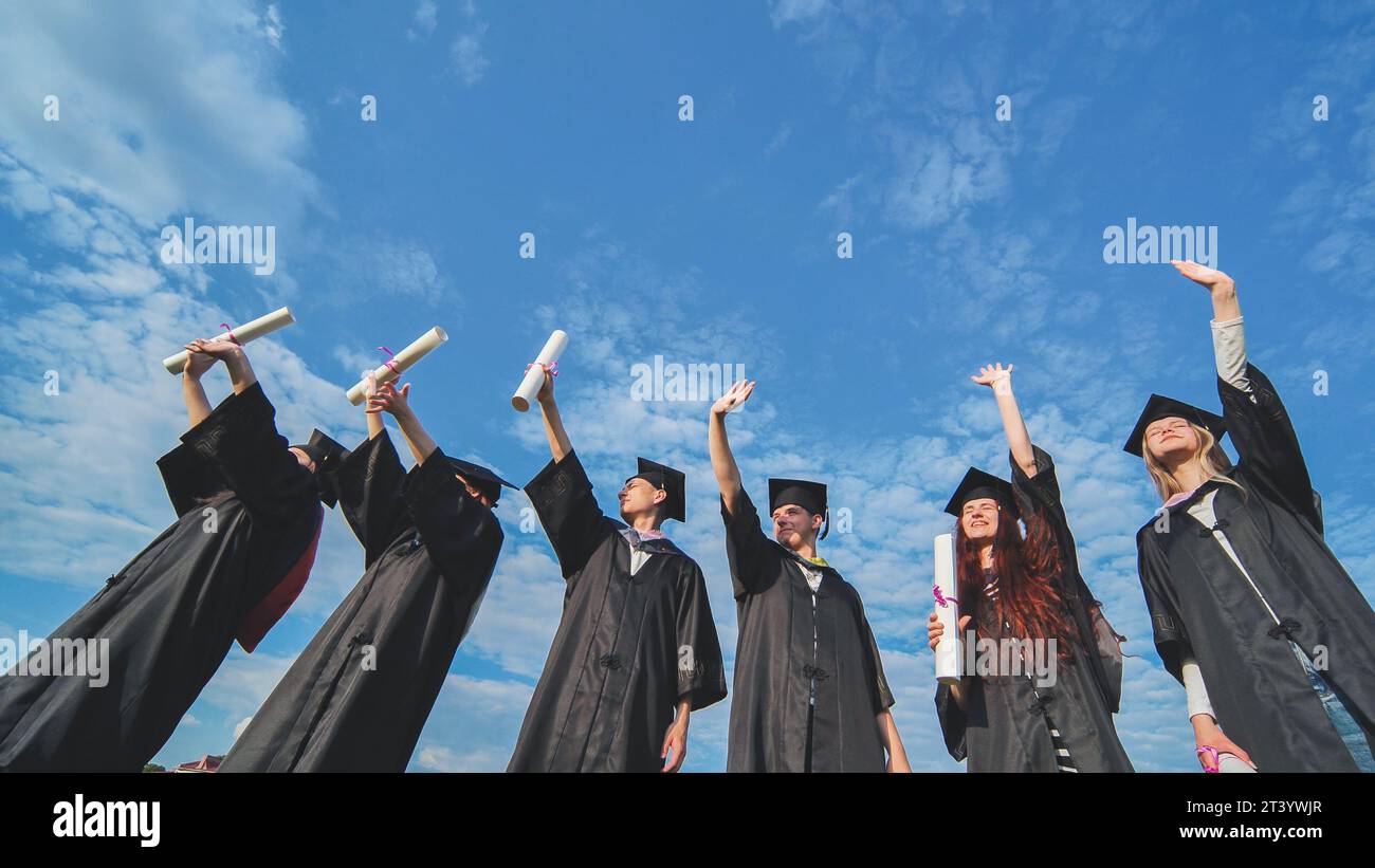 Cheerful graduates waving their diplomas on a sunny day Stock Photo - Alamy