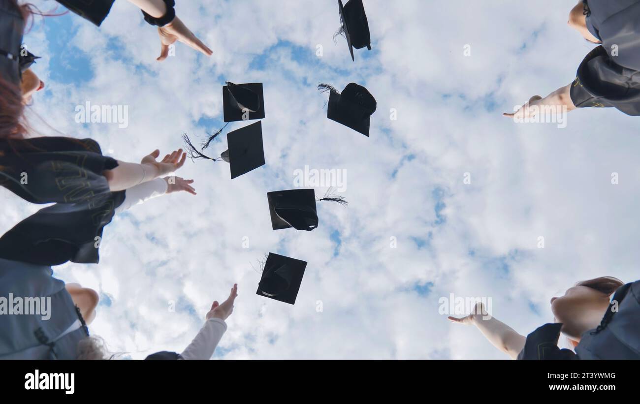 Happy group of graduated young students throwing hats Stock Photo - Alamy