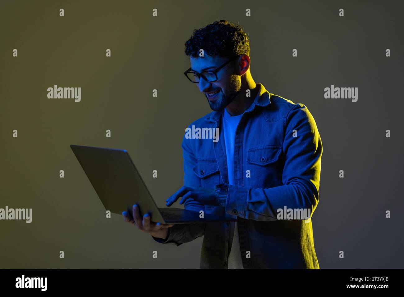Using laptop. Caucasian man's portrait isolated on blue studio ...