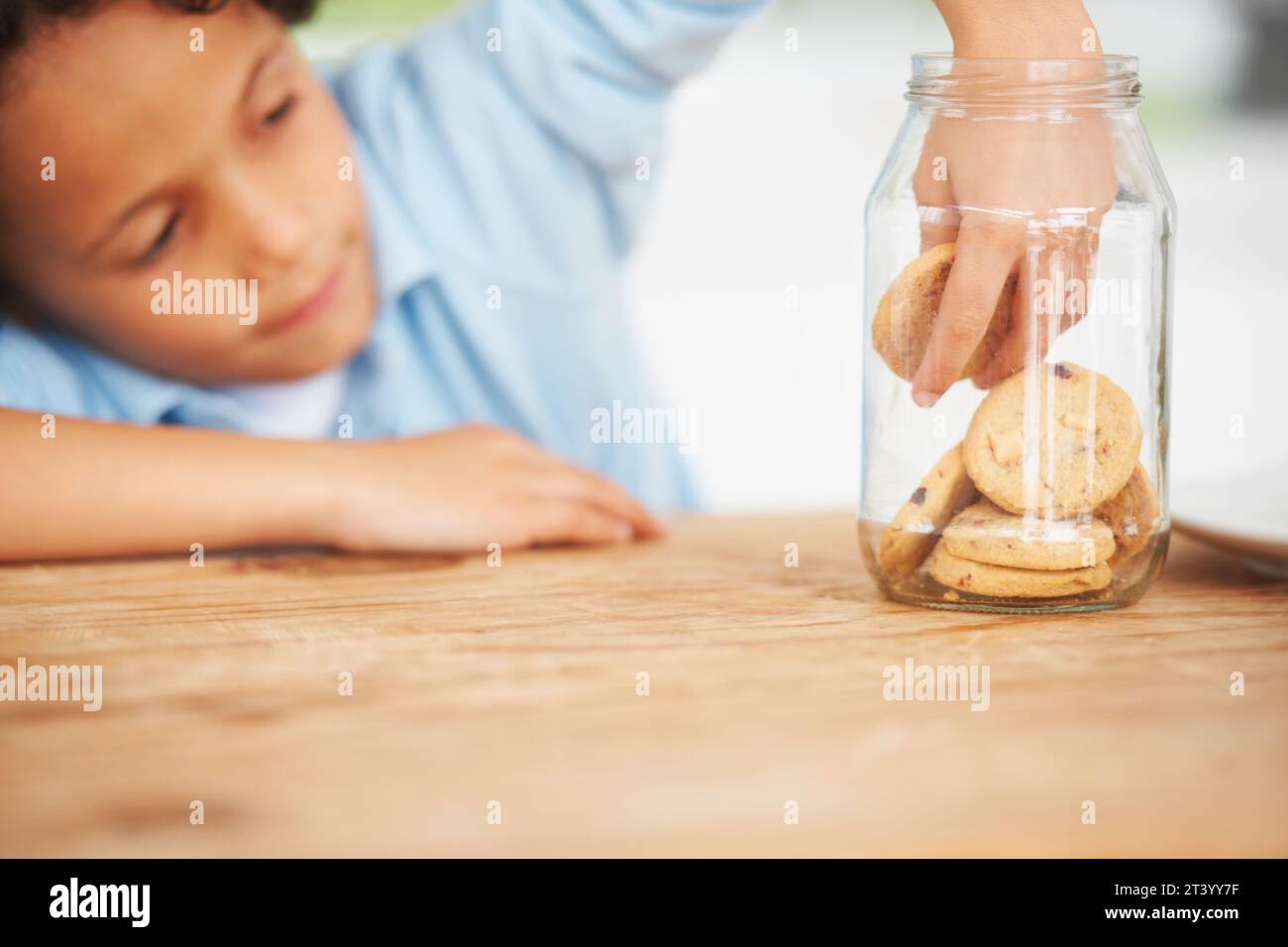 Hands, cookie jar and boy child by the kitchen counter eating a sweet ...