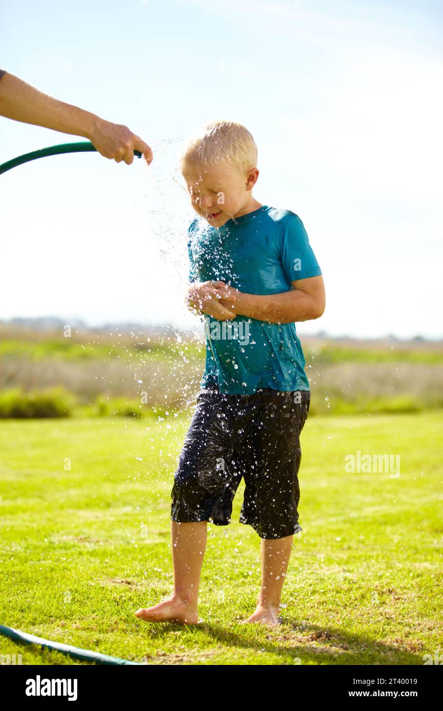 Kid, boy and hose pipe with splash, water fun and playing outdoor in ...