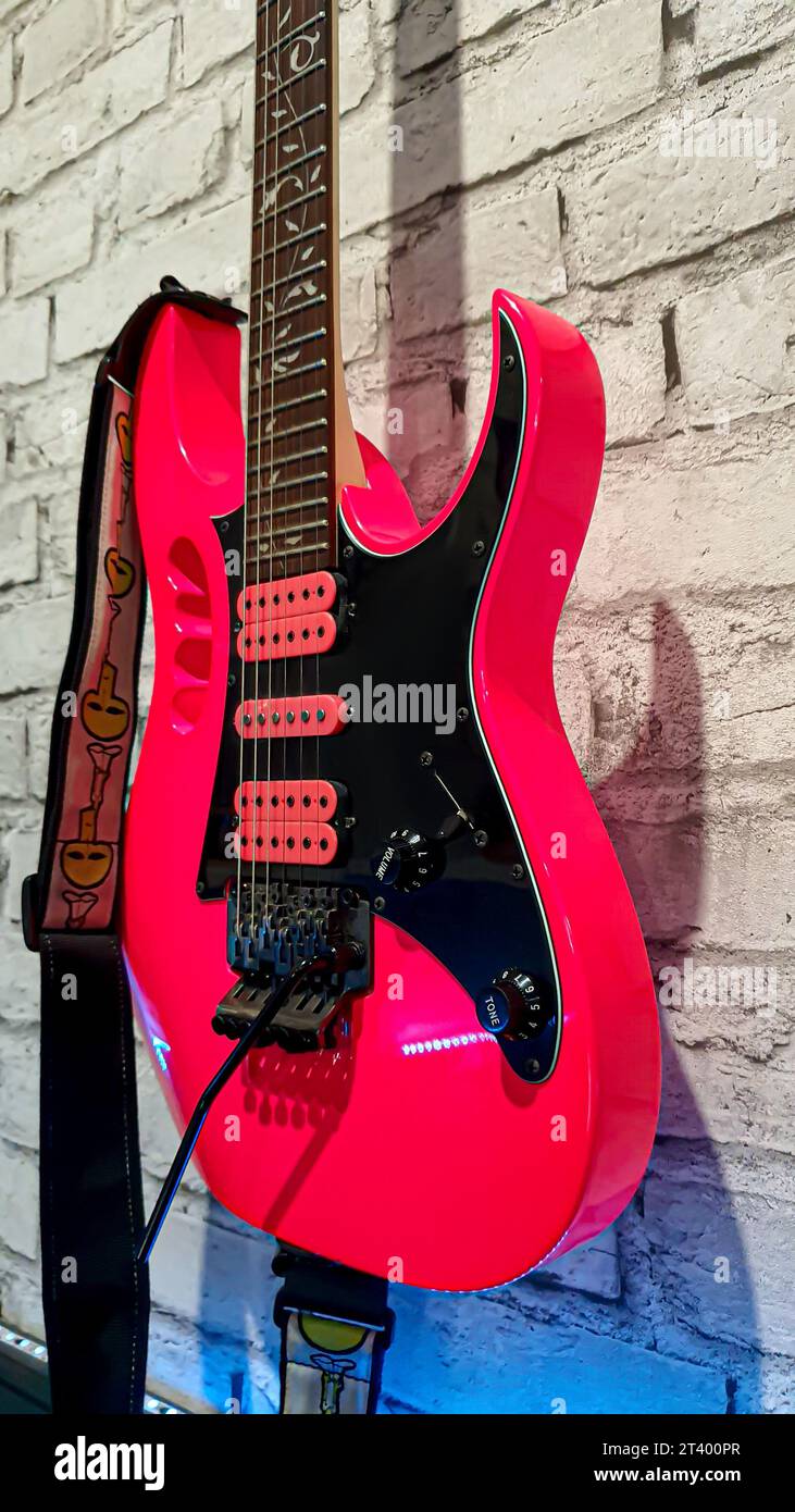 Electric guitar. Red musical instrument on a concrete wall. Copy space ...