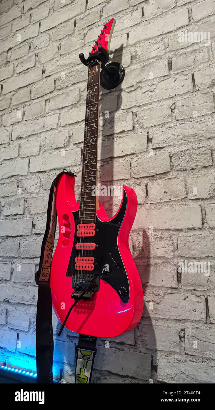 Electric guitar. Red musical instrument on a concrete wall. Copy space ...