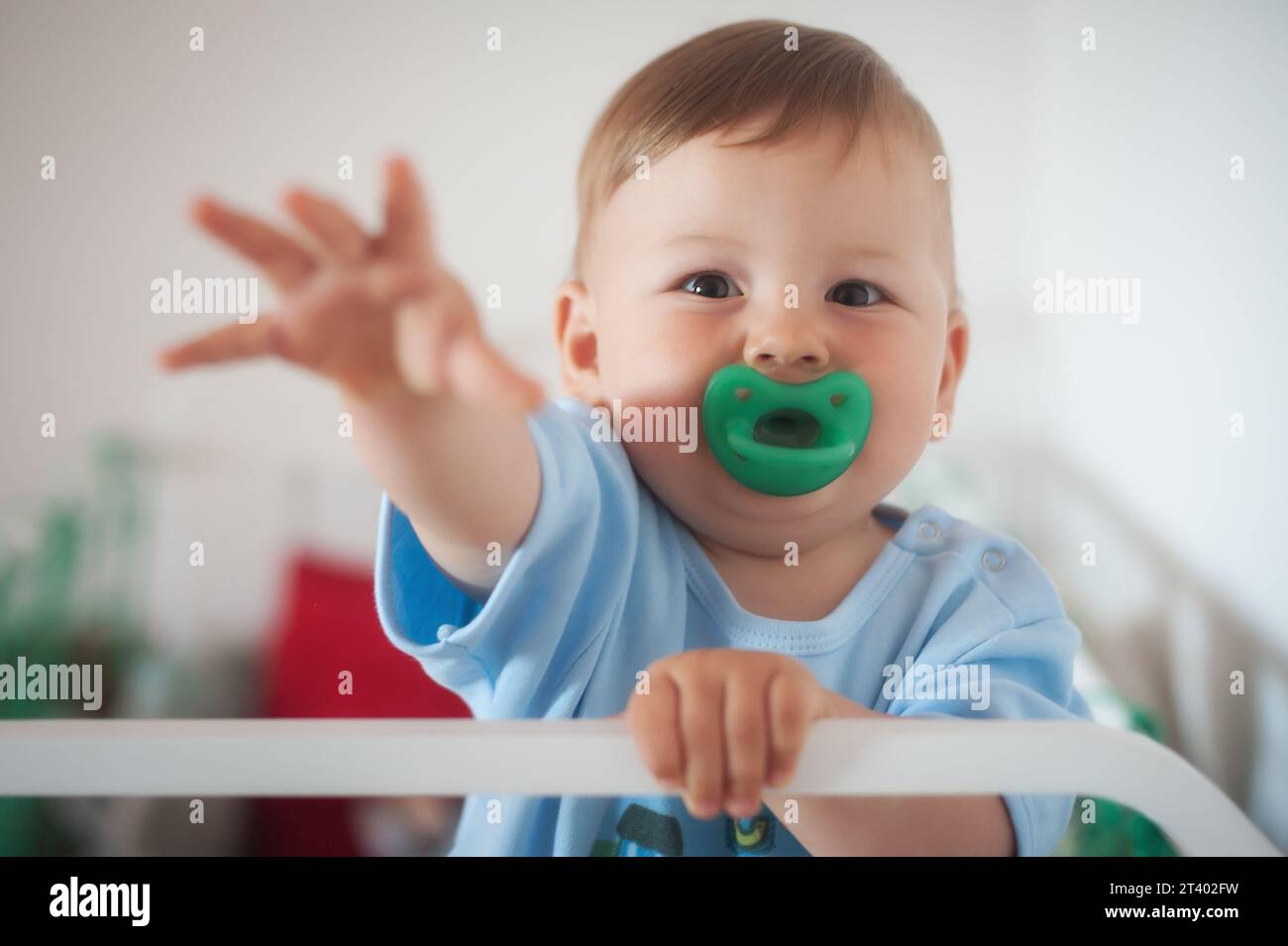 Cute baby boy stretches out his hand towards the camera in front and ...