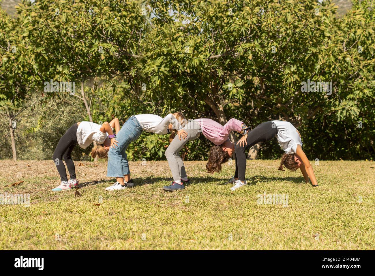 Four girls in the park doing acrobatic exercises. Children playing ...