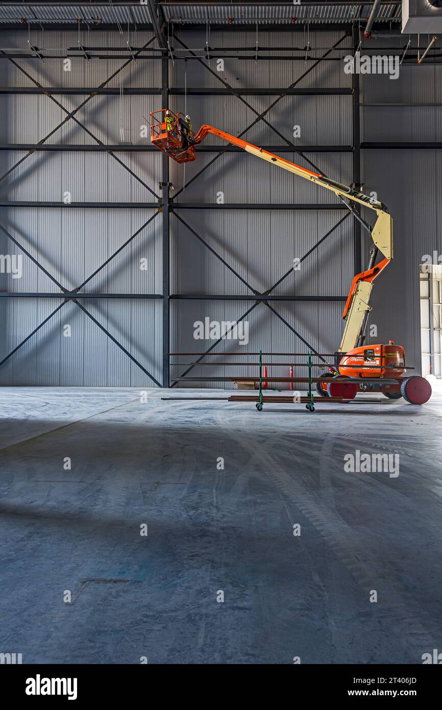 An articulated-arm man-lift (cherry-picker) in front of a wall in a ...