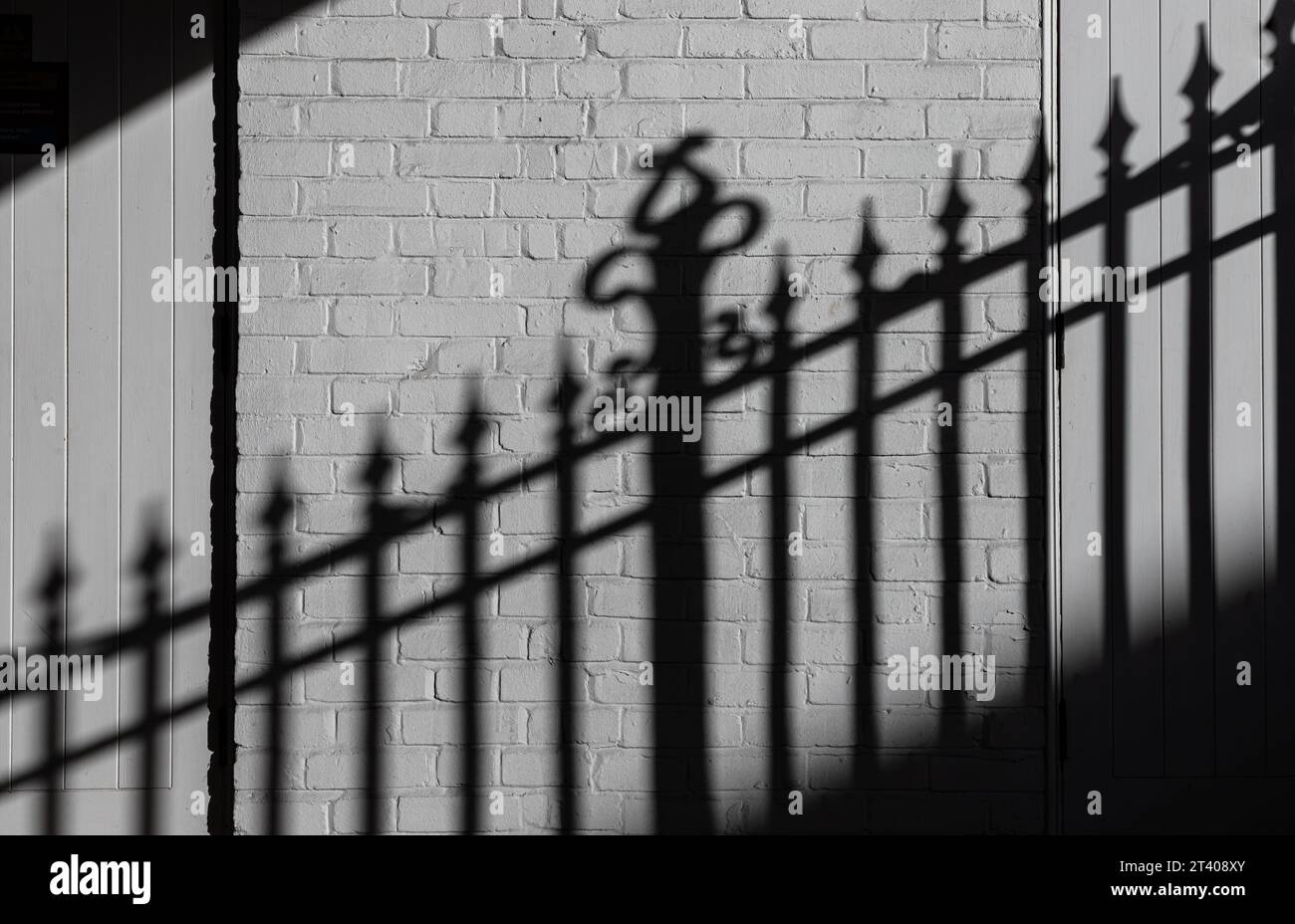 Wrought iron fence casts its stark shadow reflected on the adjacent ...