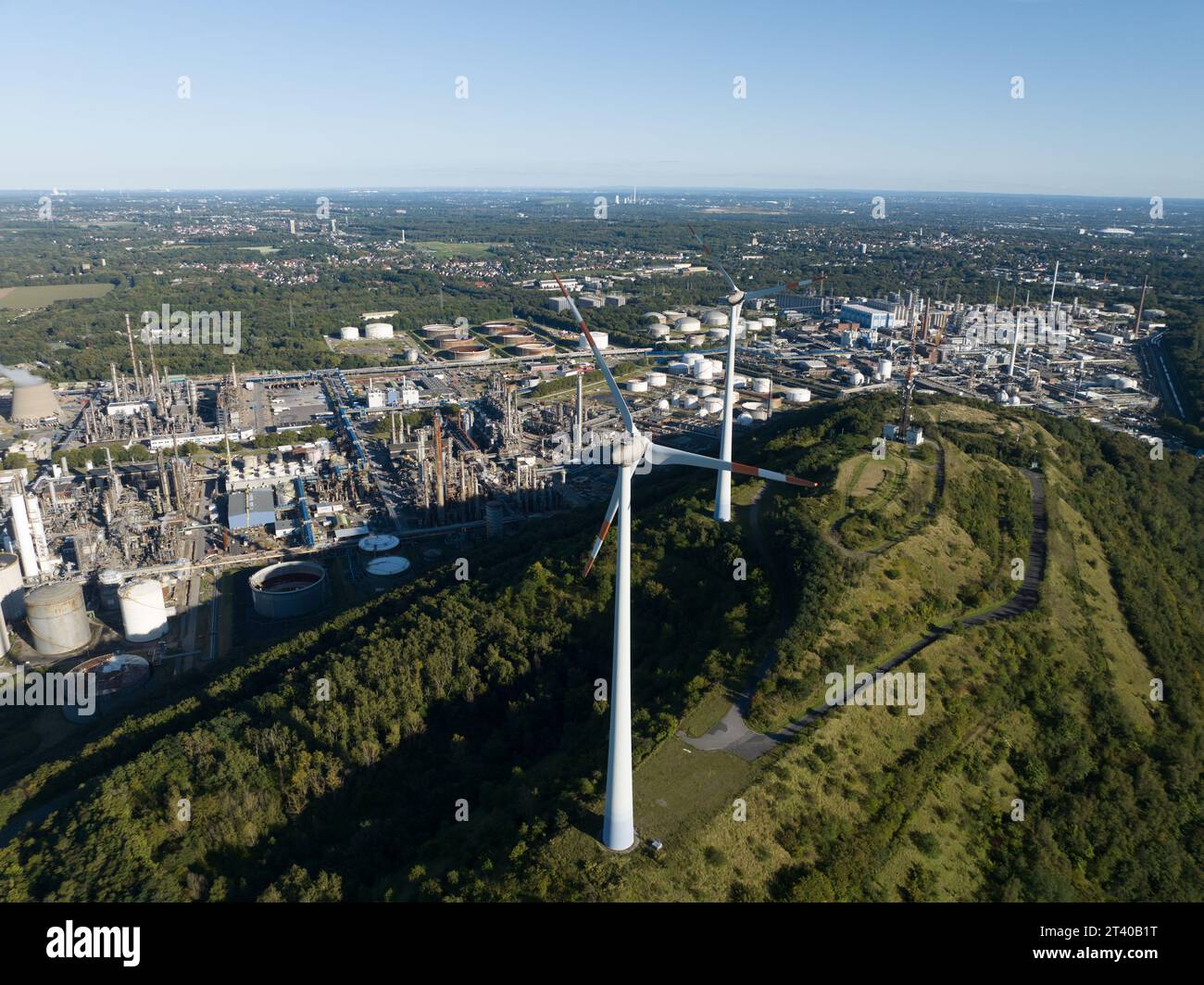 Wind turbines on hill in heavy industrial zone. Petrochemical industry ...