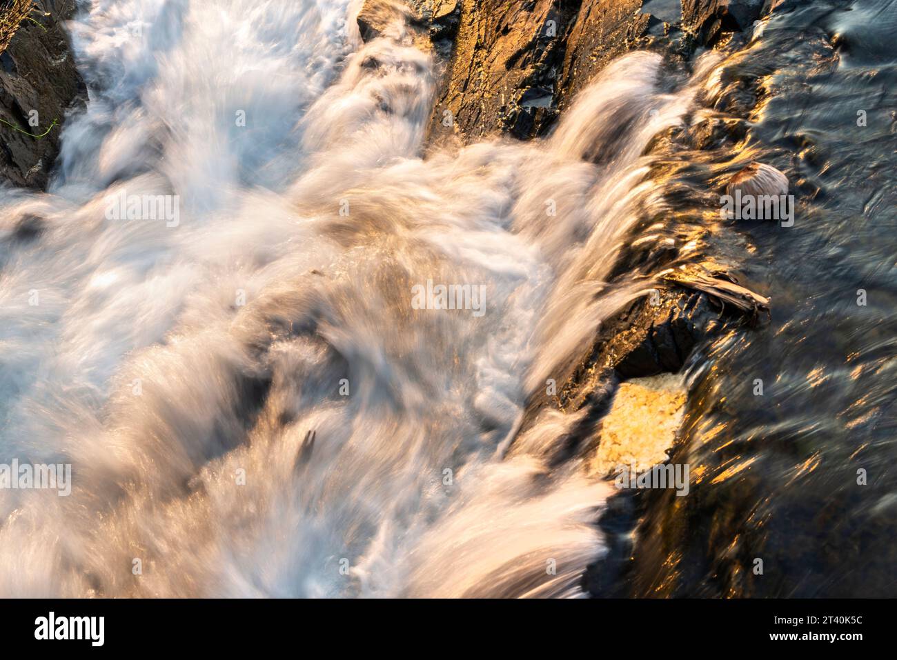 Abstract details of water movemet,at sunset.Sunlight shining on rocks ...