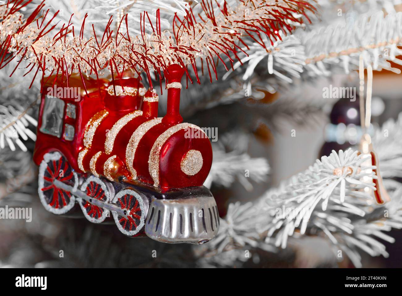 Close-up of red train hanging on Cristmas tree agains white branches ...