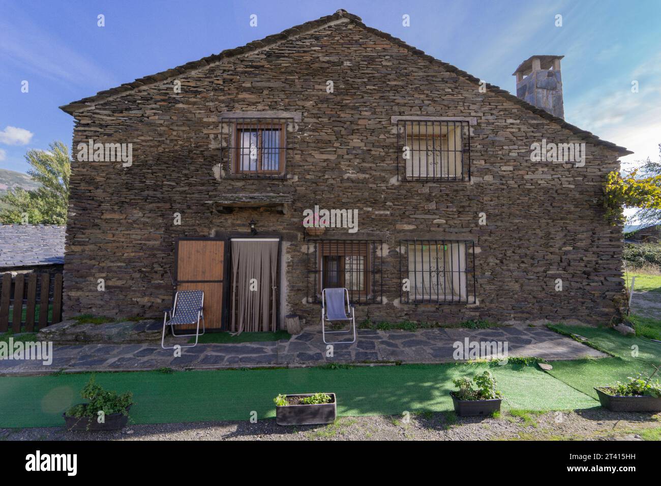 Large stone house with several windows and several chairs on the ...