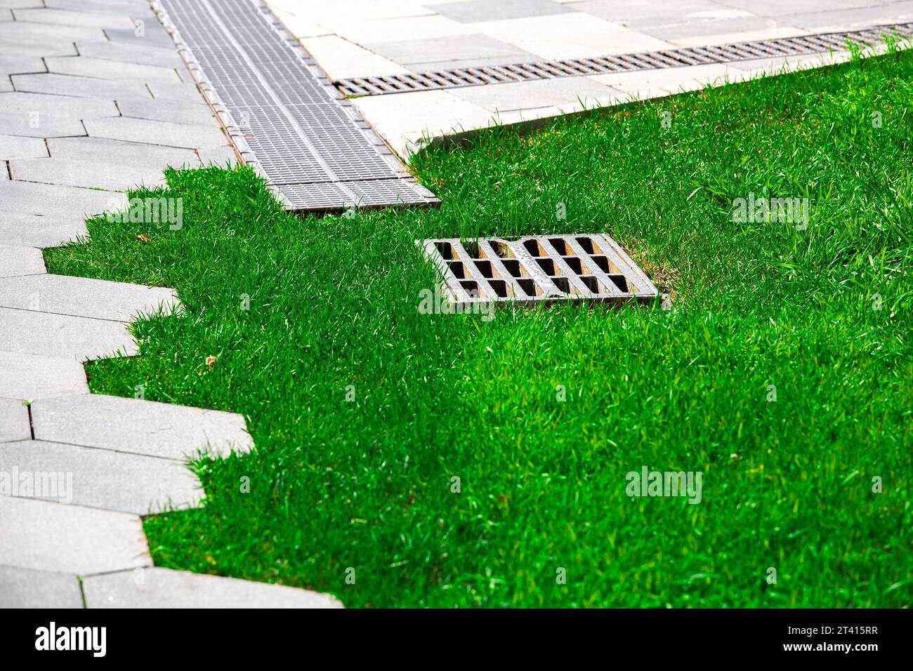 pavement with stone tiles decorative pattern and trimmed green lawn on ...