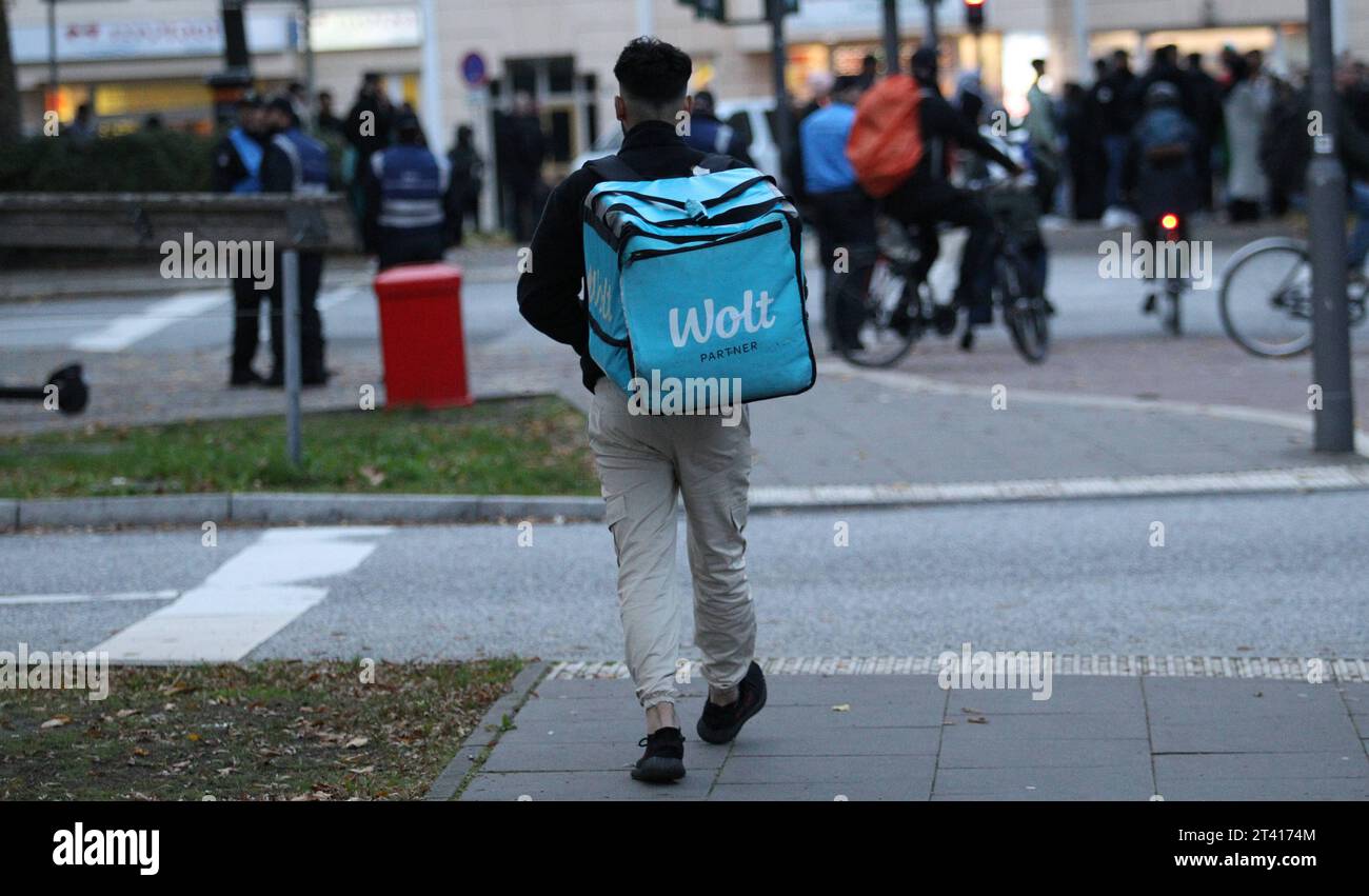 Ein Kurier vom Lieferservice Wolt geht eine Straße in St. Georg entlang ...