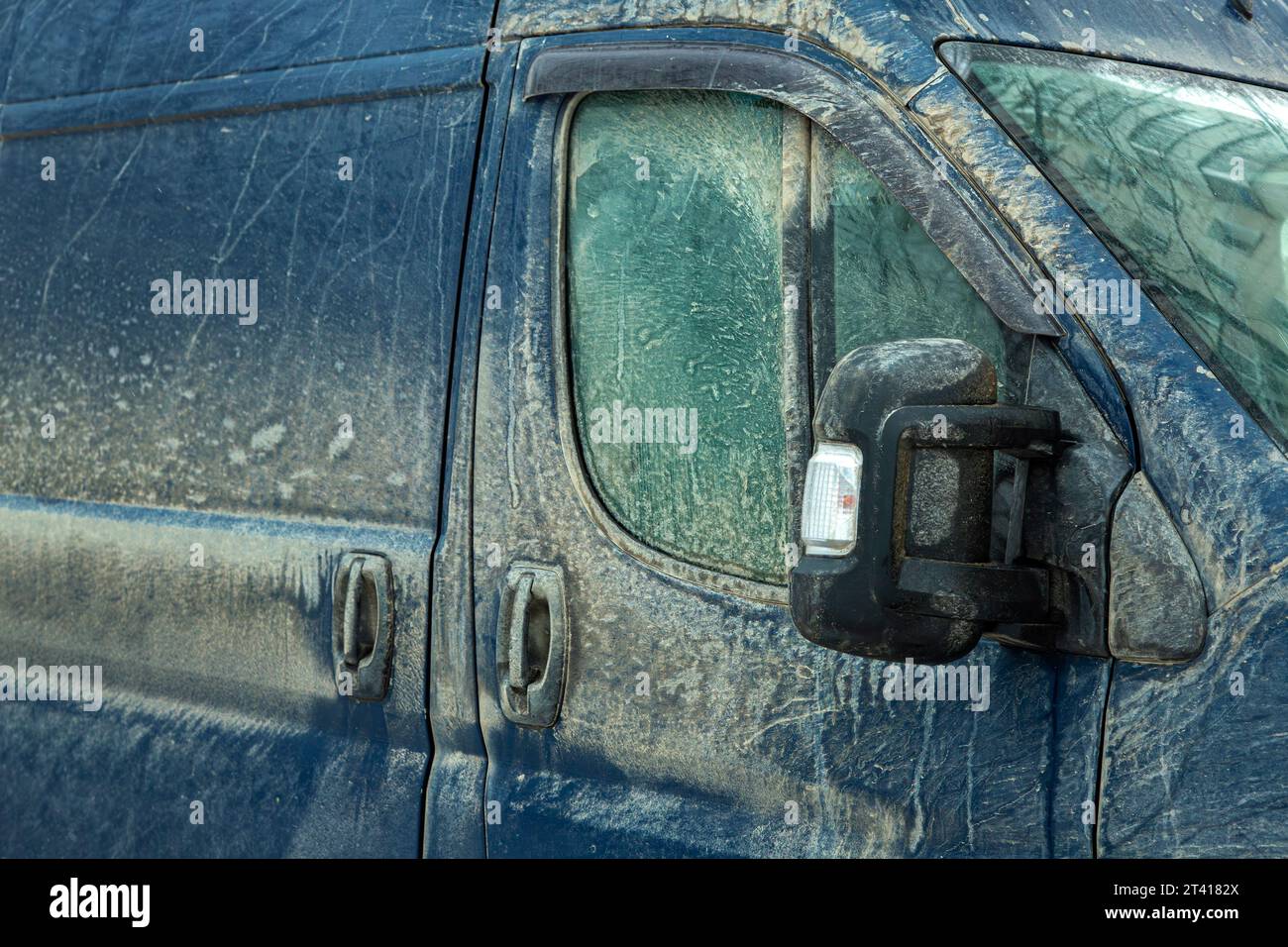 a cargo van covered in a layer of dirt, the front door with a window ...