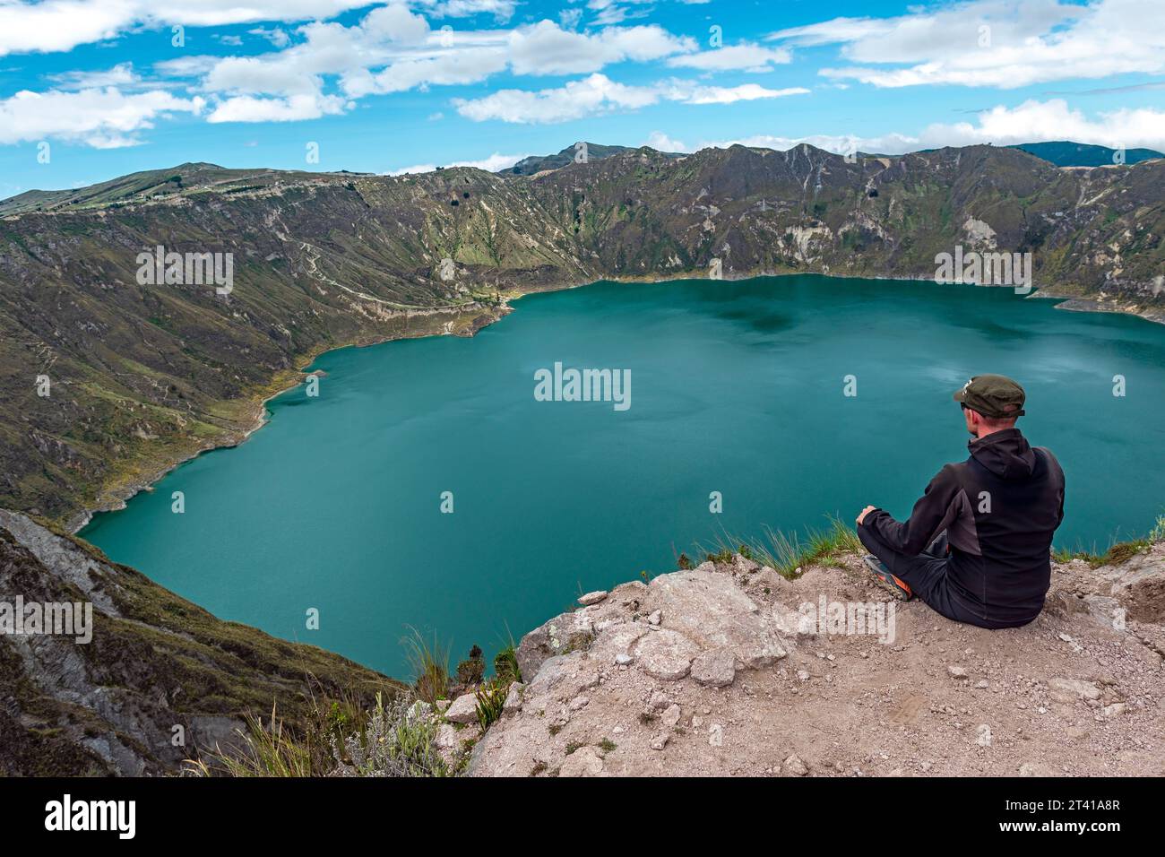 Male tourist hiker looking over Quilotoa Lake along the Quilotoa Lagoon ...