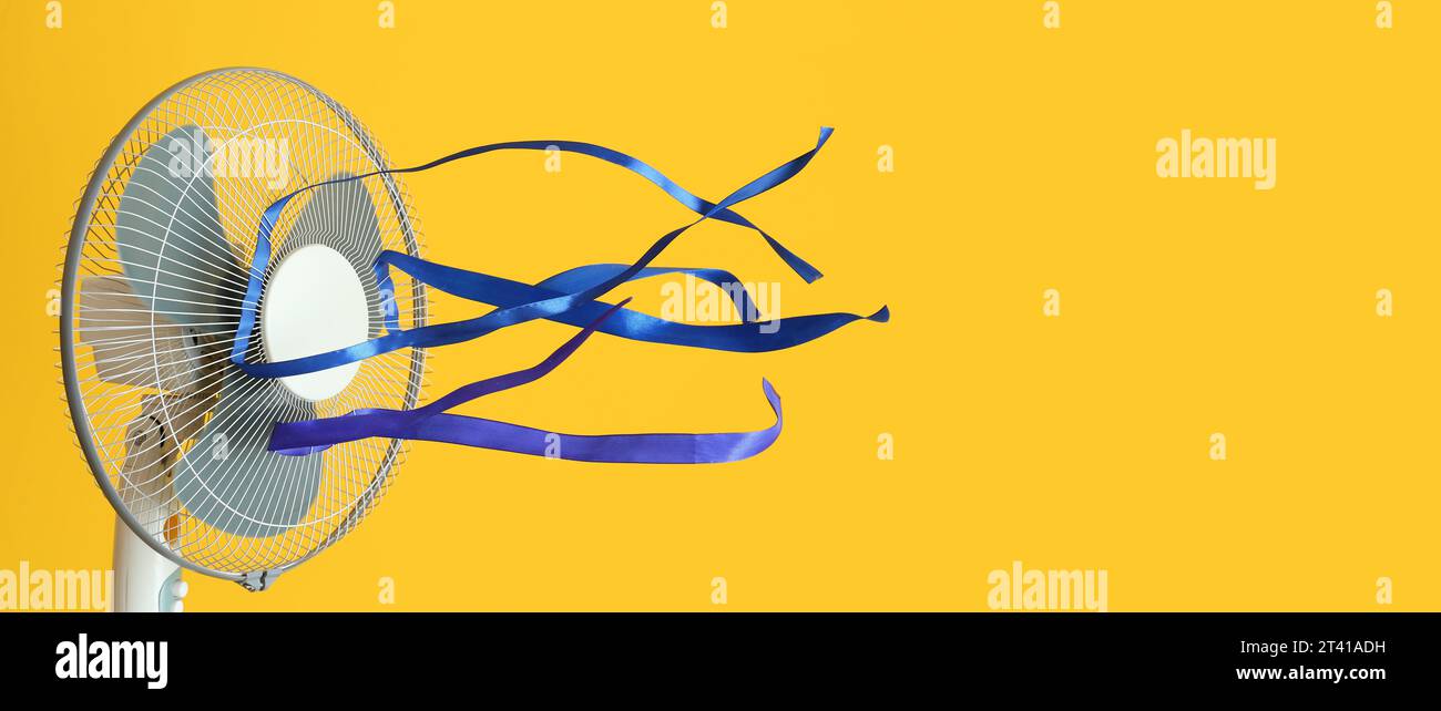 Electric fan and fluttering ribbons on yellow background with space for ...