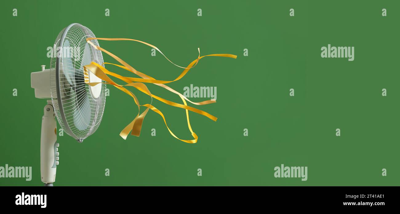 Electric fan and fluttering ribbons on green background with space for ...