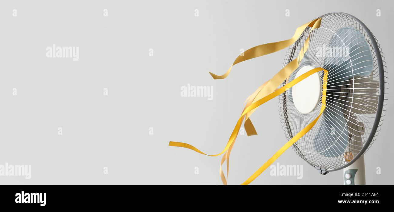 Electric fan and fluttering ribbons on light background with space for ...