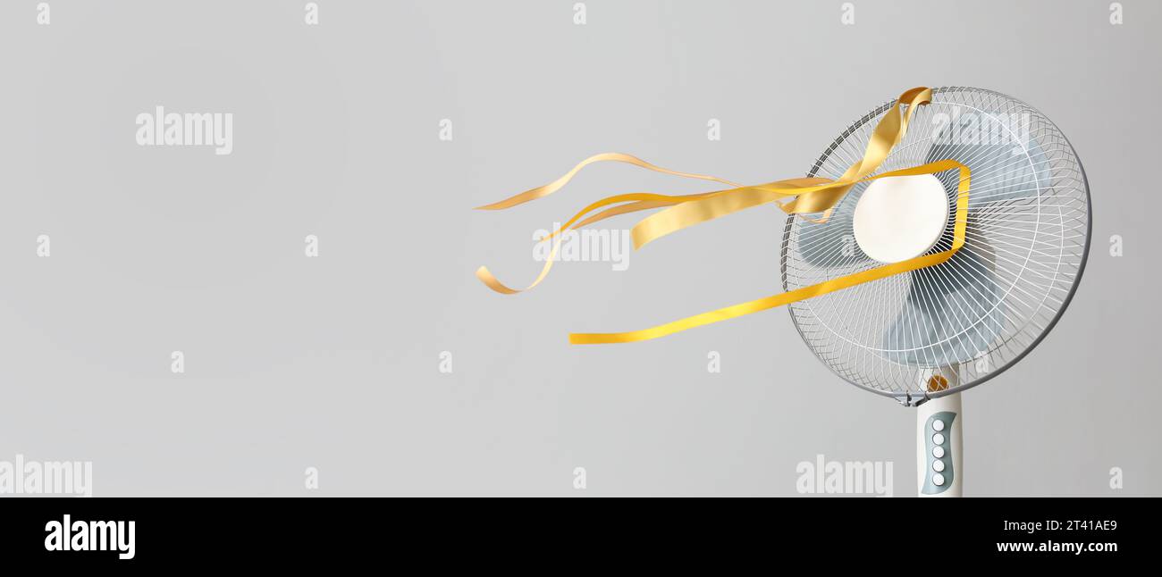 Electric fan and fluttering ribbons on light background with space for ...