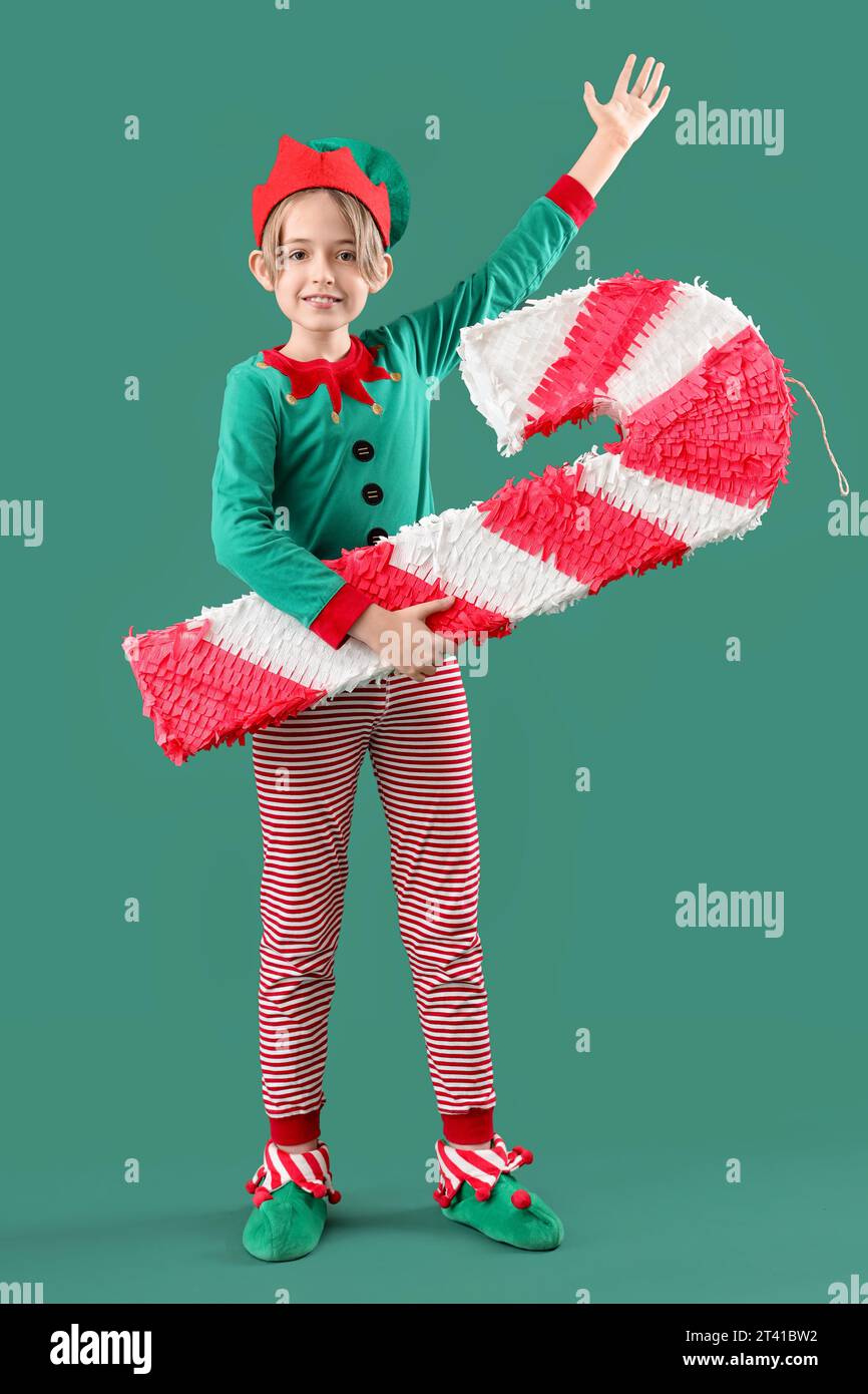 Cute little boy in elf costume with candy cane pinata on green ...