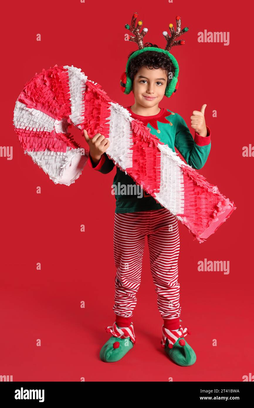 Cute little boy in elf costume with candy cane pinata showing thumb-up ...