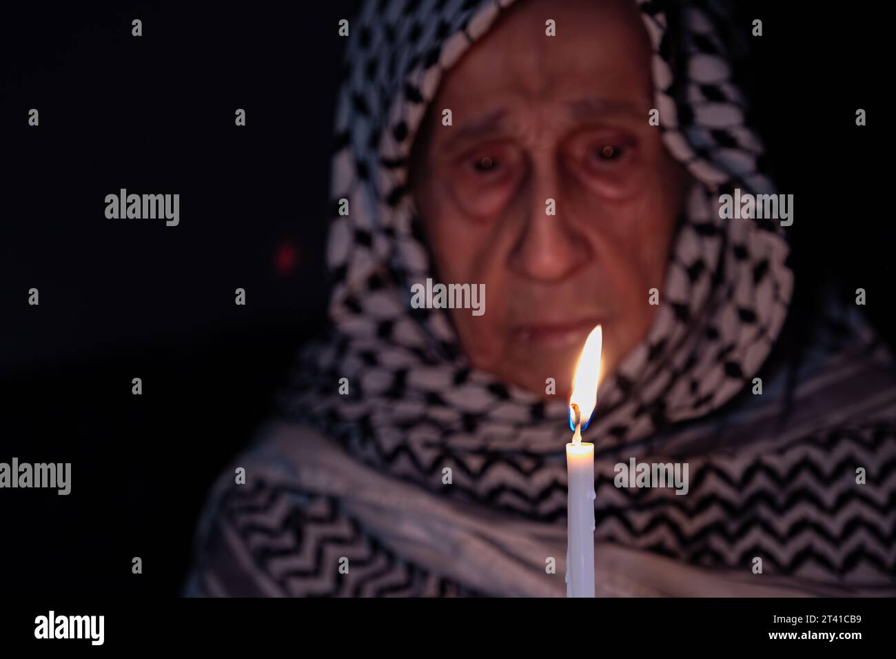 Portrait of old lady wearing white palestinian keffiyeh in dark holding ...