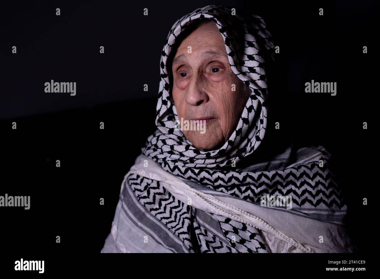 portrait of an old lady in dark background wearing white palestinian ...