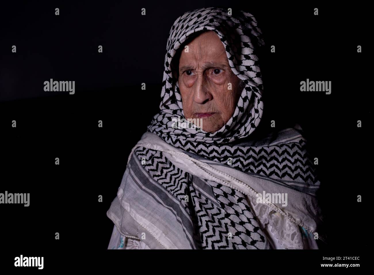 portrait of an old lady in dark background wearing white palestinian ...