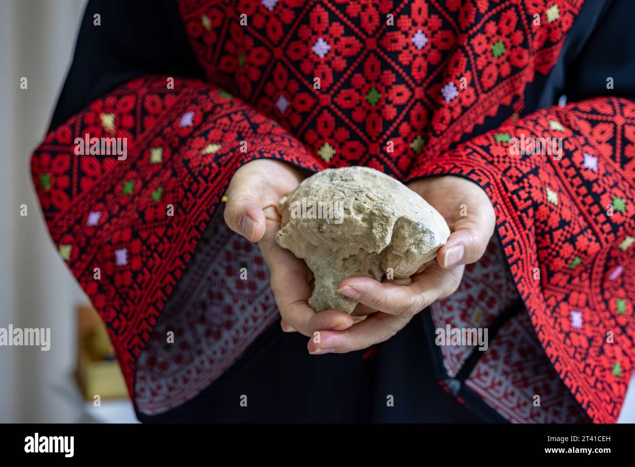 A Palestinian woman holds a stone in her hands, which represents the ...